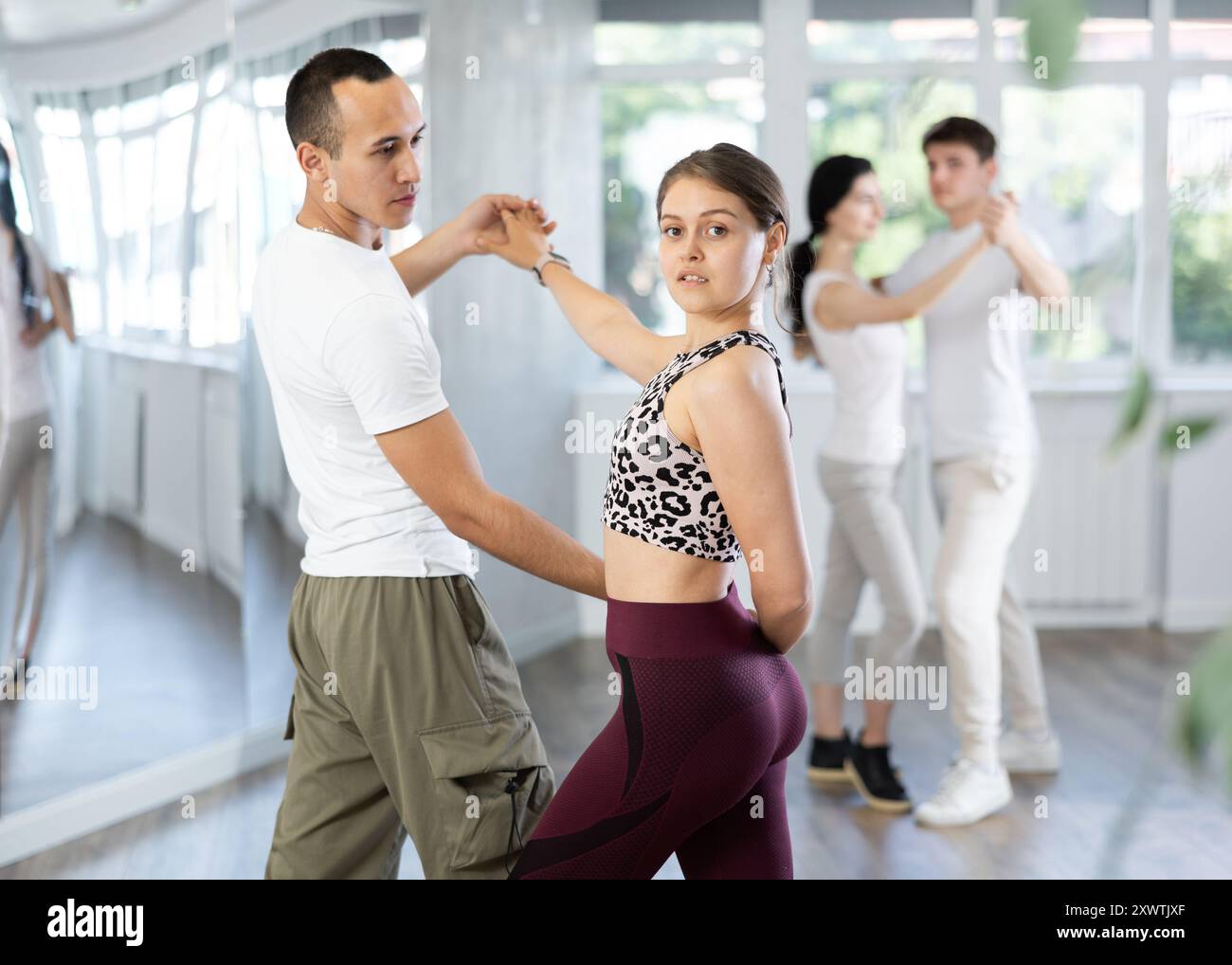 Positive girl dancing playful bachata with partner in studio Stock ...