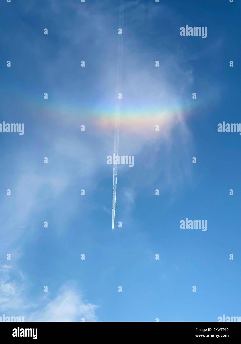 A jet passing overhead leaves a rainbow sun dog from it's vapour trail ...