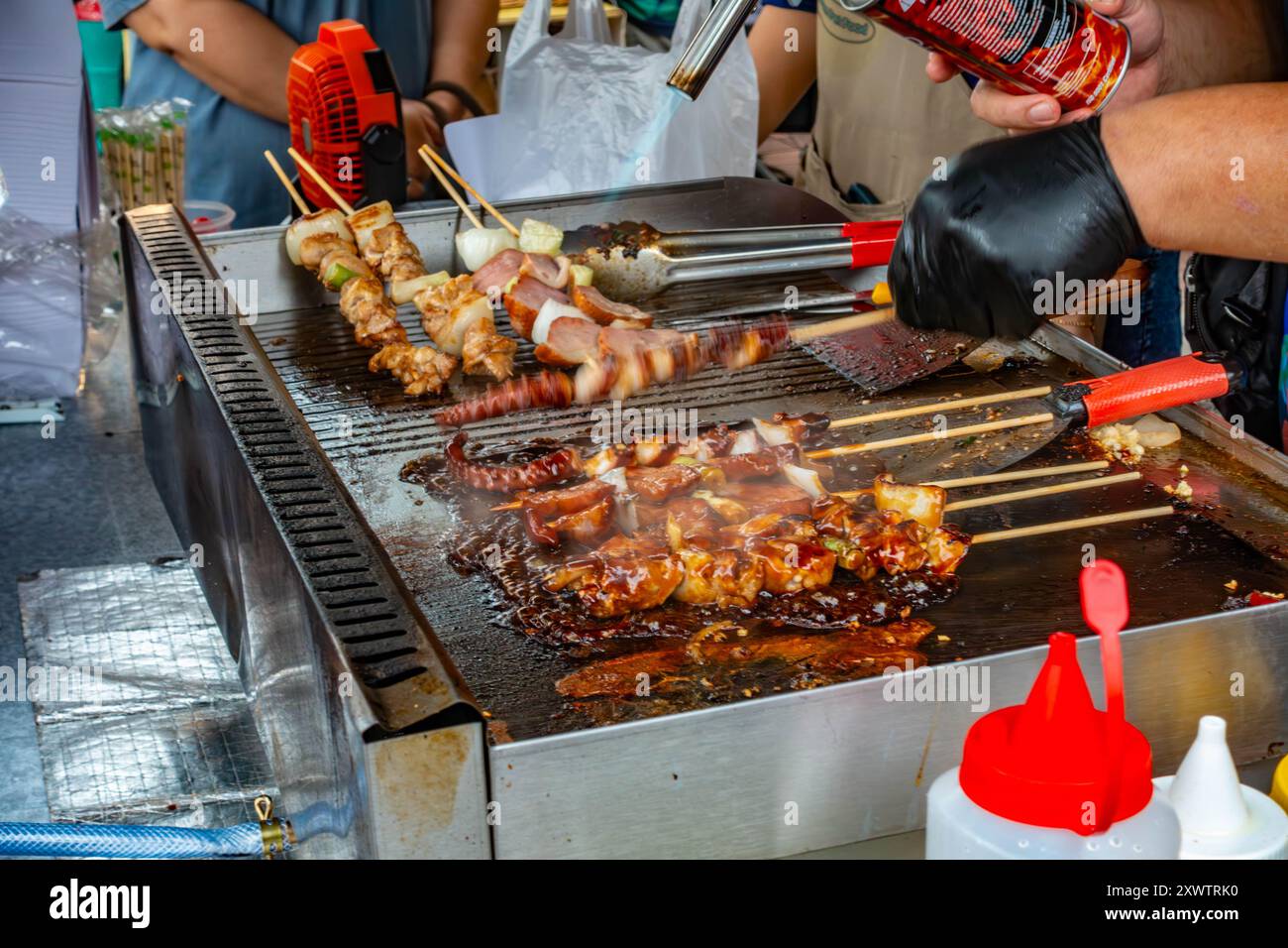 Pork kebabs on wooden skewers being cooked at a market stall in Tanjung ...