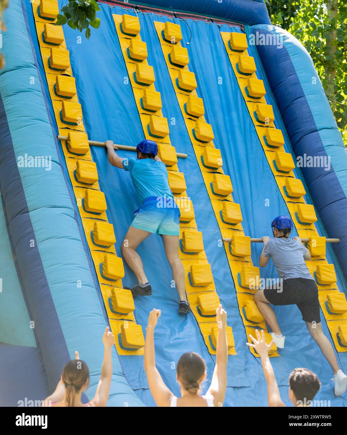 Two male friends climbing on inflatable slide with wooden poles Stock ...