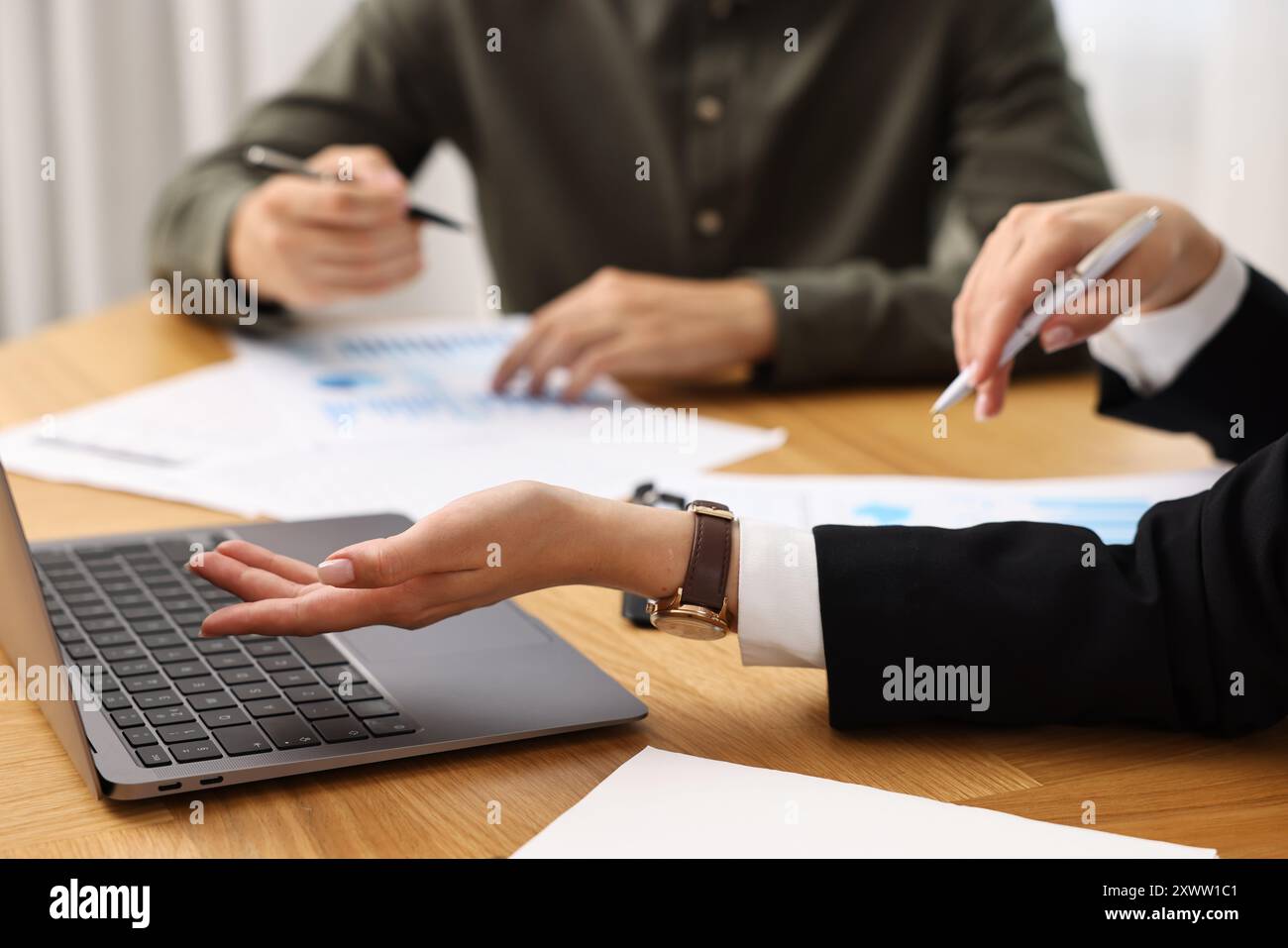 Consultant working with client at wooden table in office, closeup ...