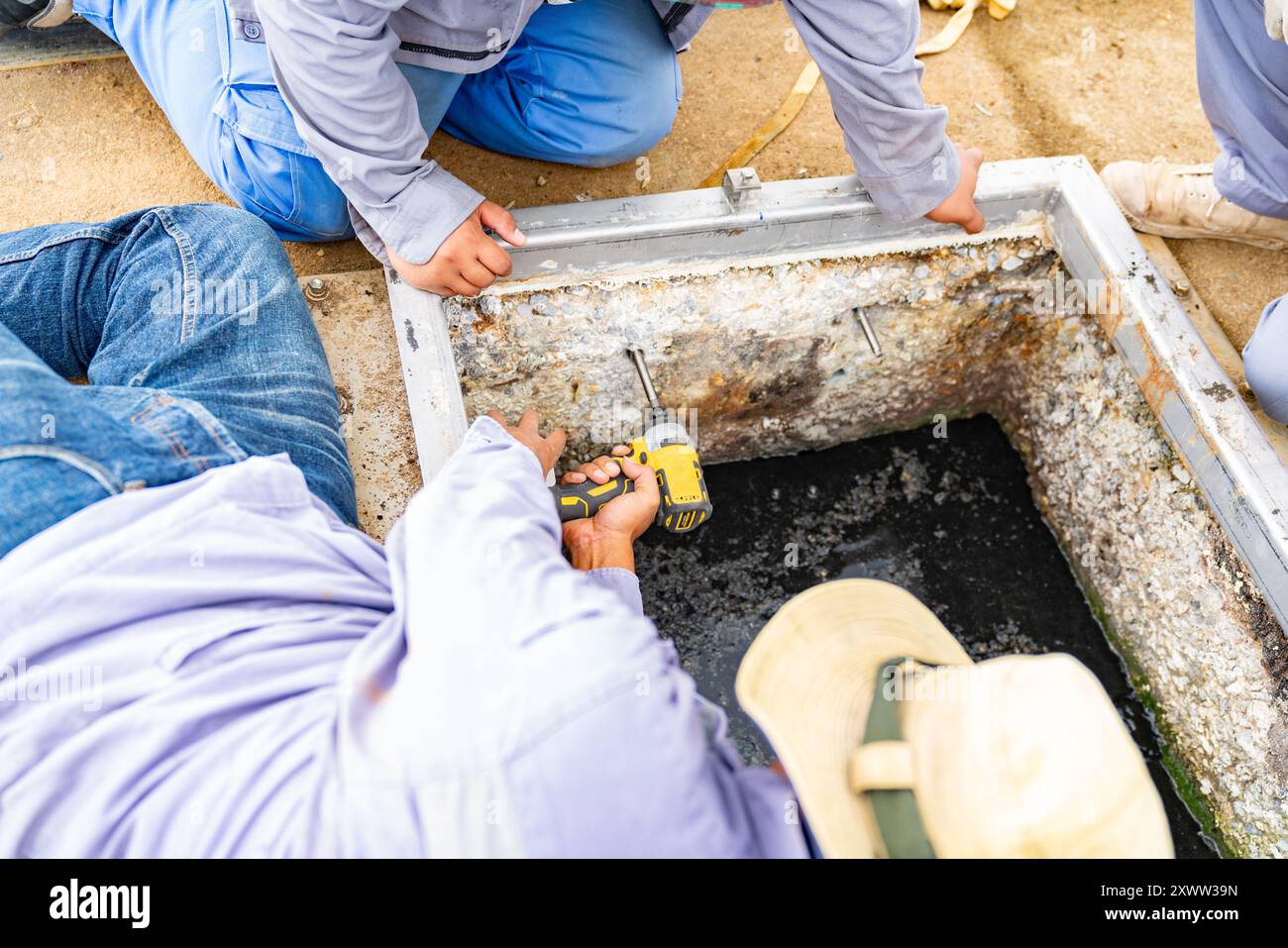 Technician install screw into the concrete wall of treatment pit with a ...