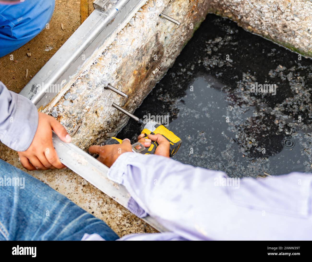 Technician install screw into the concrete wall of treatment pit with a ...