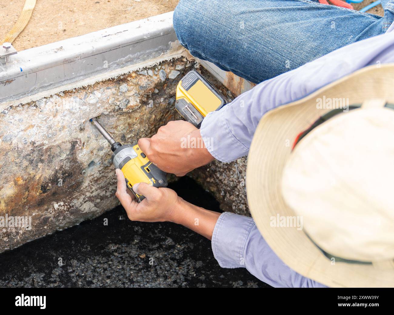 Technician drilling screw on concrete wall of treatment pit with ...