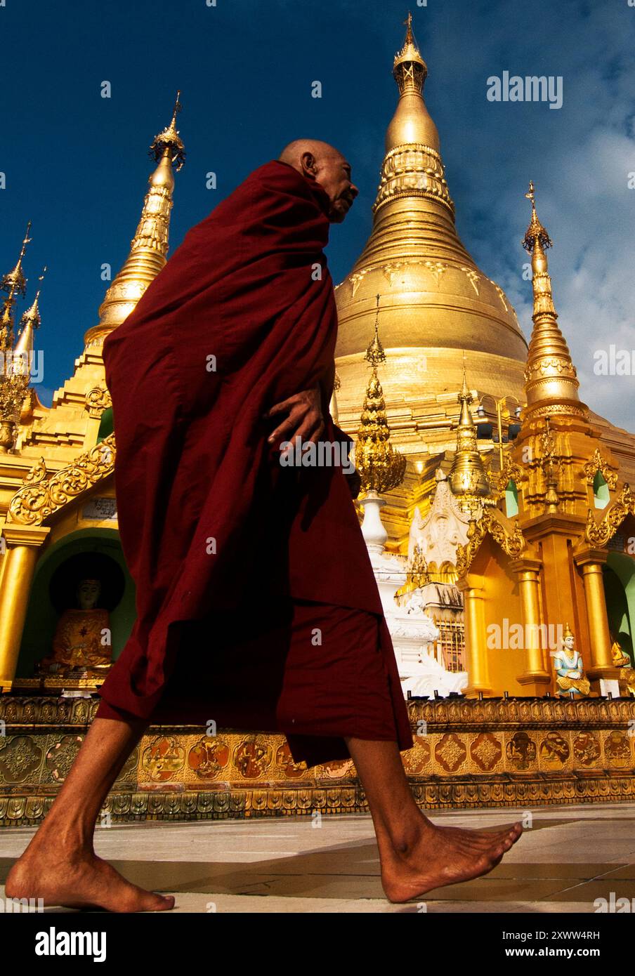 A Buddhist monk walking by the Shwedagon pagoda in Yangon, Myanmar ...