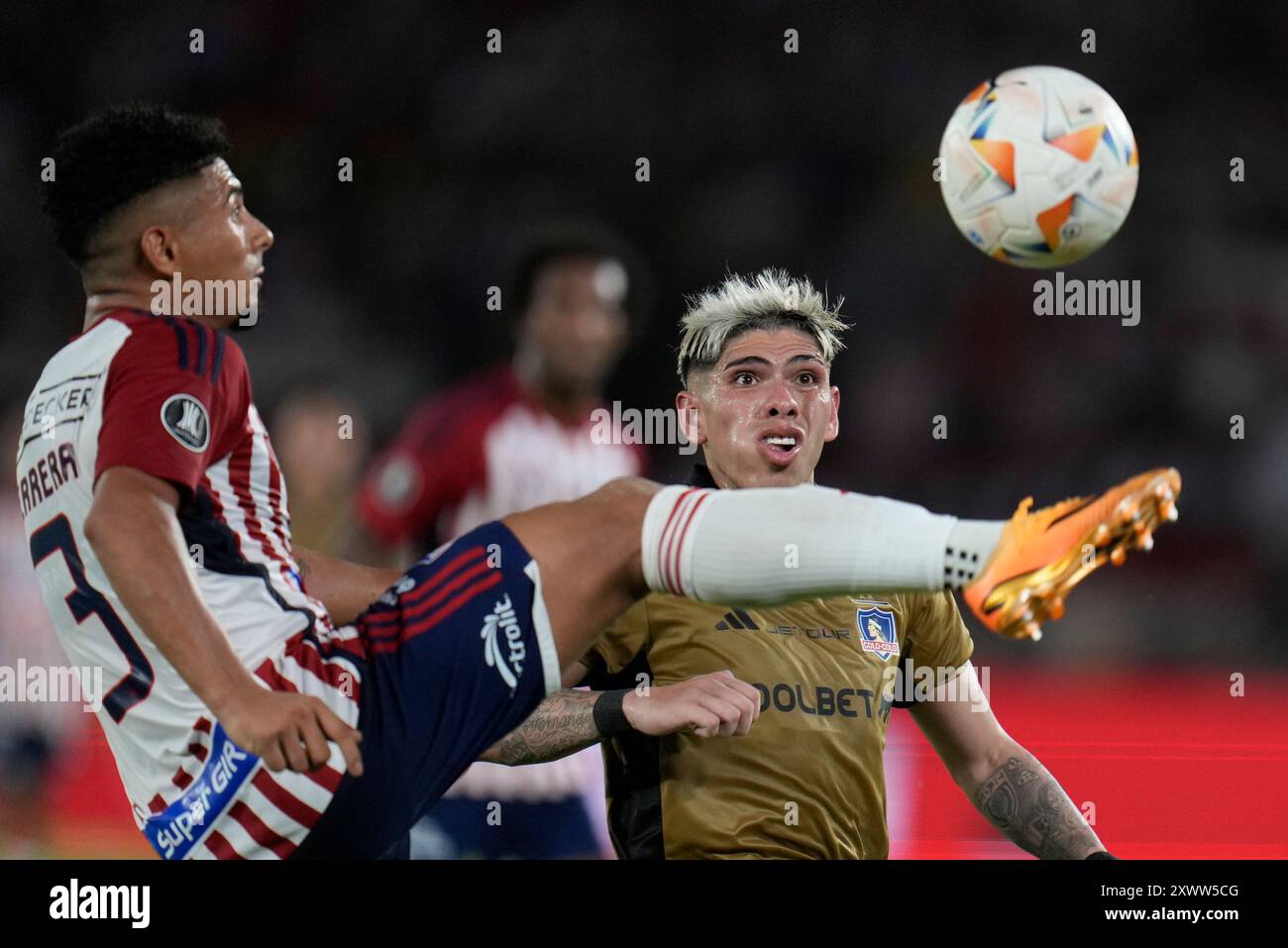 Edwin Herrera, left, of Colombia's Junior hits the ball alongside ...