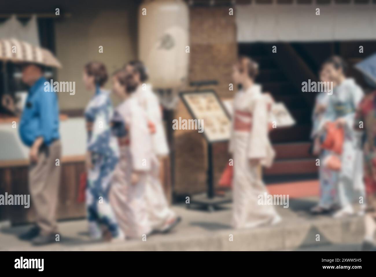 Blurry image of a street scene in Japan with people in traditional ...