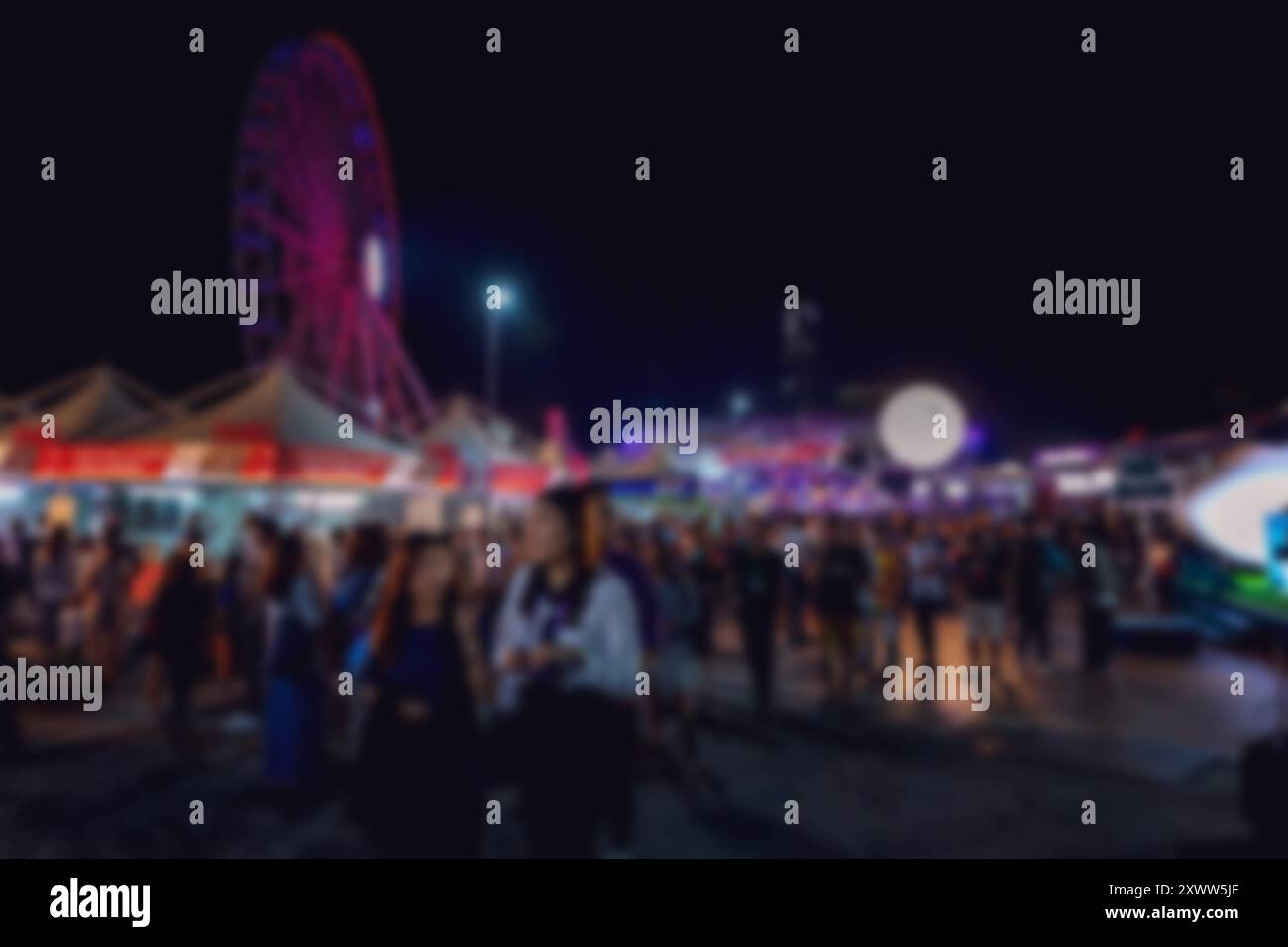 A blurred night scene of a Hong Kong crowd walking past food stalls and ...