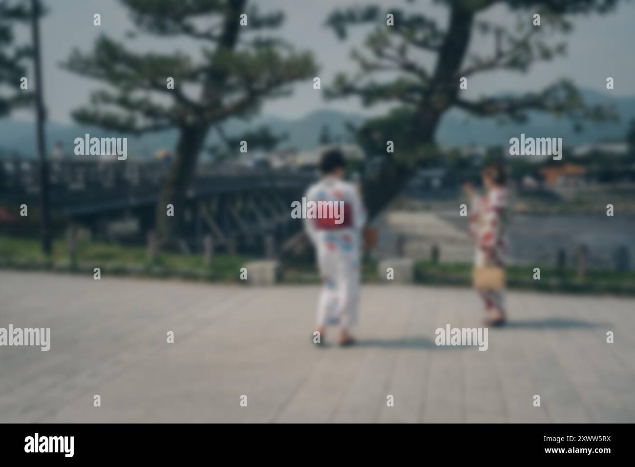 Two women wearing traditional Japanese clothing walk along a paved path ...