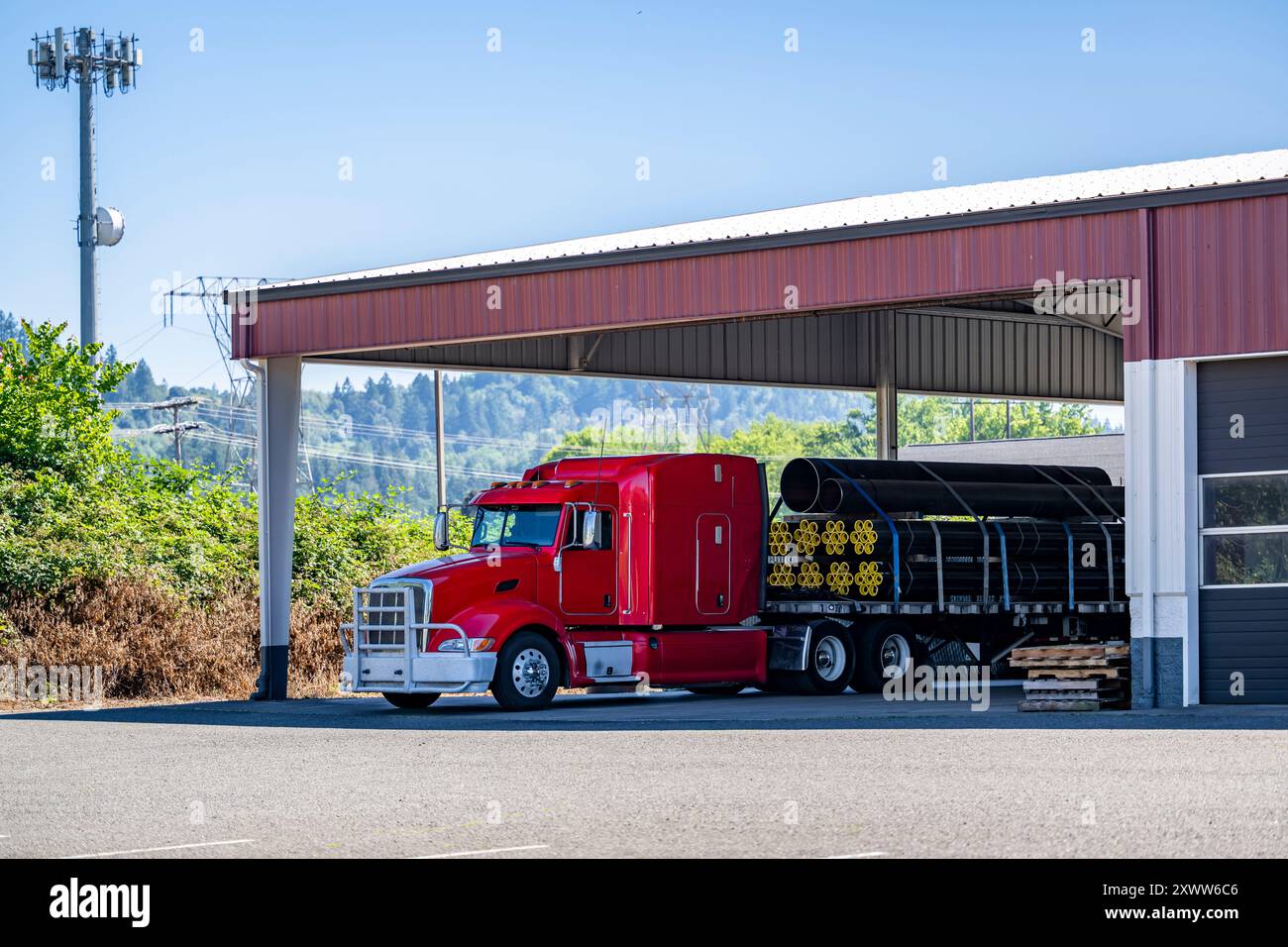 Industrial red big rig semi truck with grille guard and loaded flat bed ...