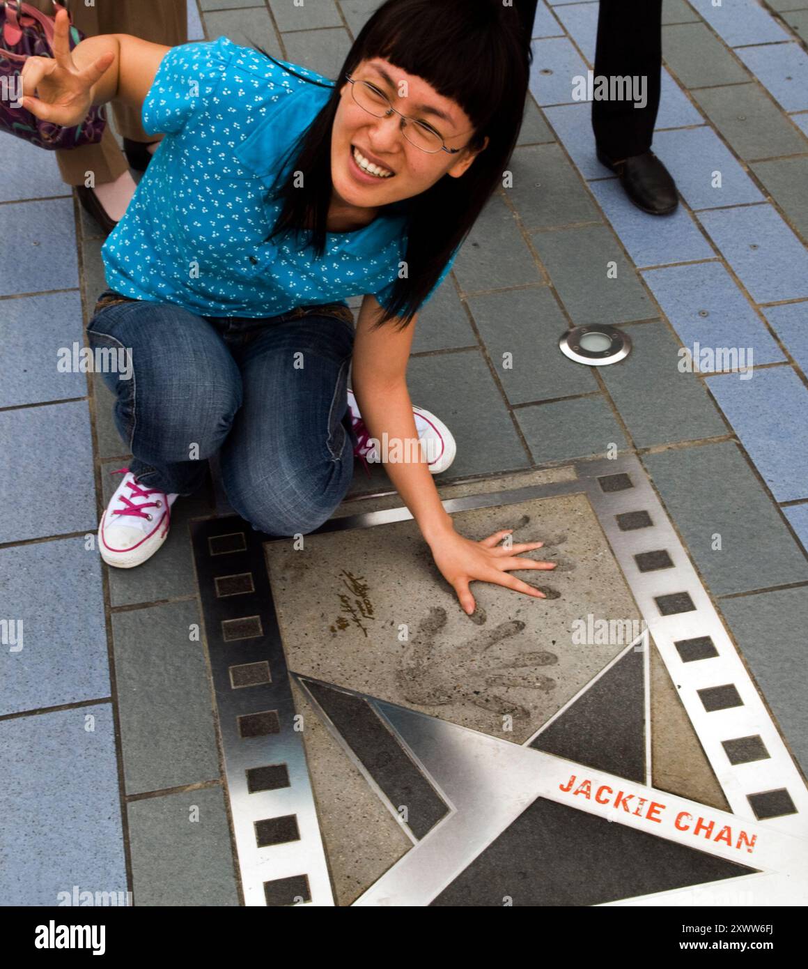 A tourist posing by the handprint of Jackie Chan at the Avenue of the ...