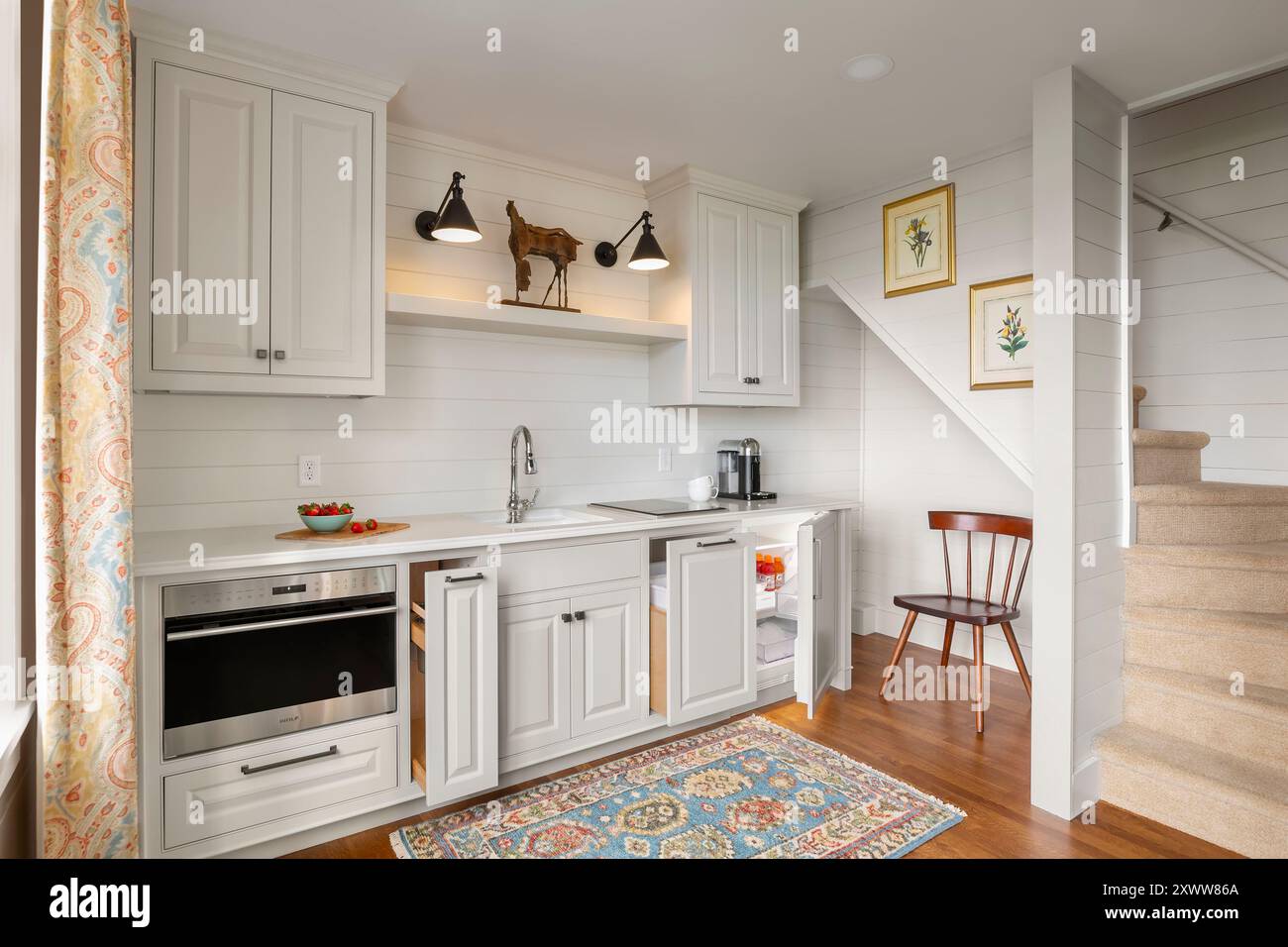 A small kitchen in a guest house with stairs leading upstairs with ...