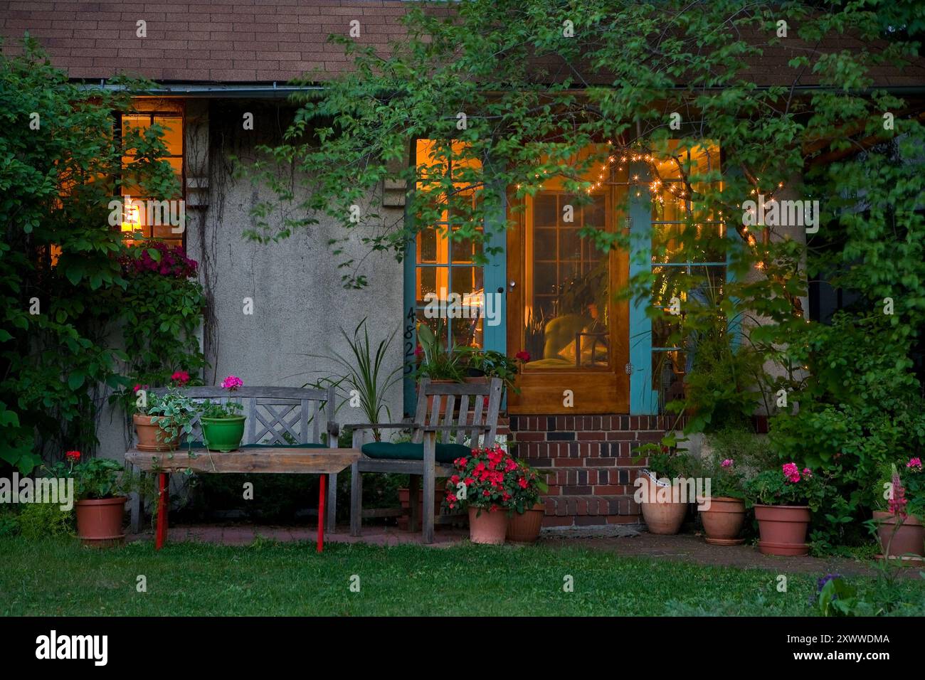 Appealing house entrance with string lights and interior lights on at ...