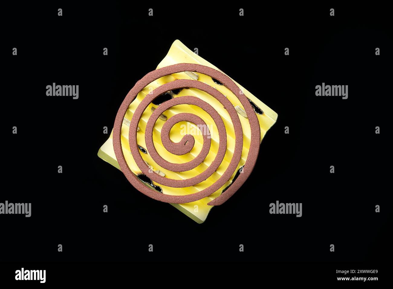 A yellow piece of paper with a mosquito coils on it. A brown object is ...