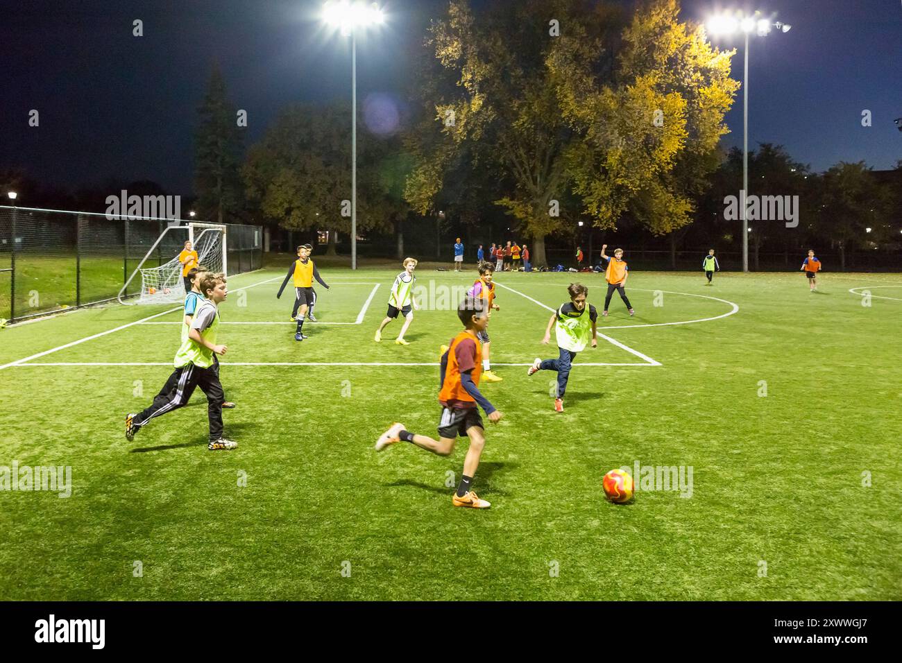 Young boys playing soccer at night Stock Photo - Alamy