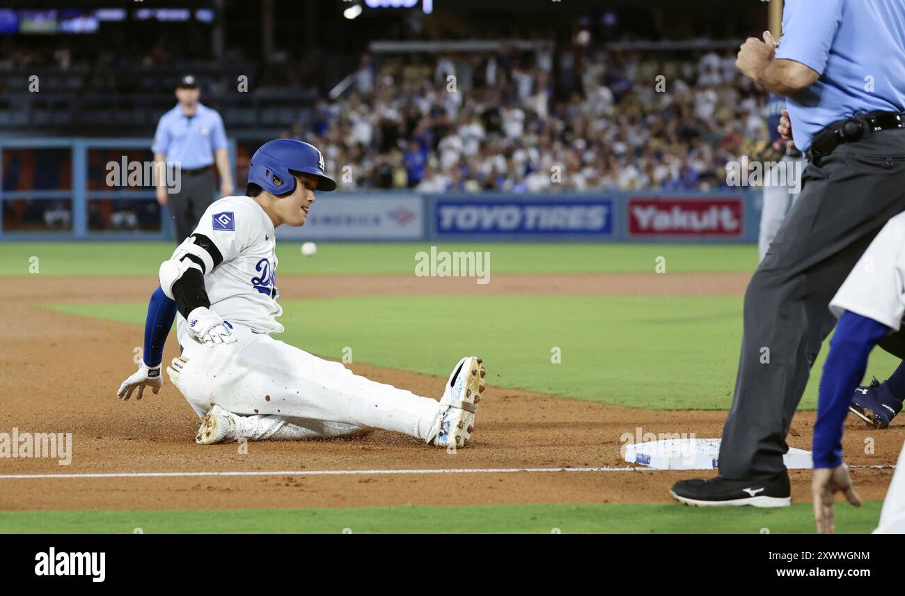 Los Angeles Dodgers designated hitter Shohei Ohtani slides to third base after hitting a triple ...