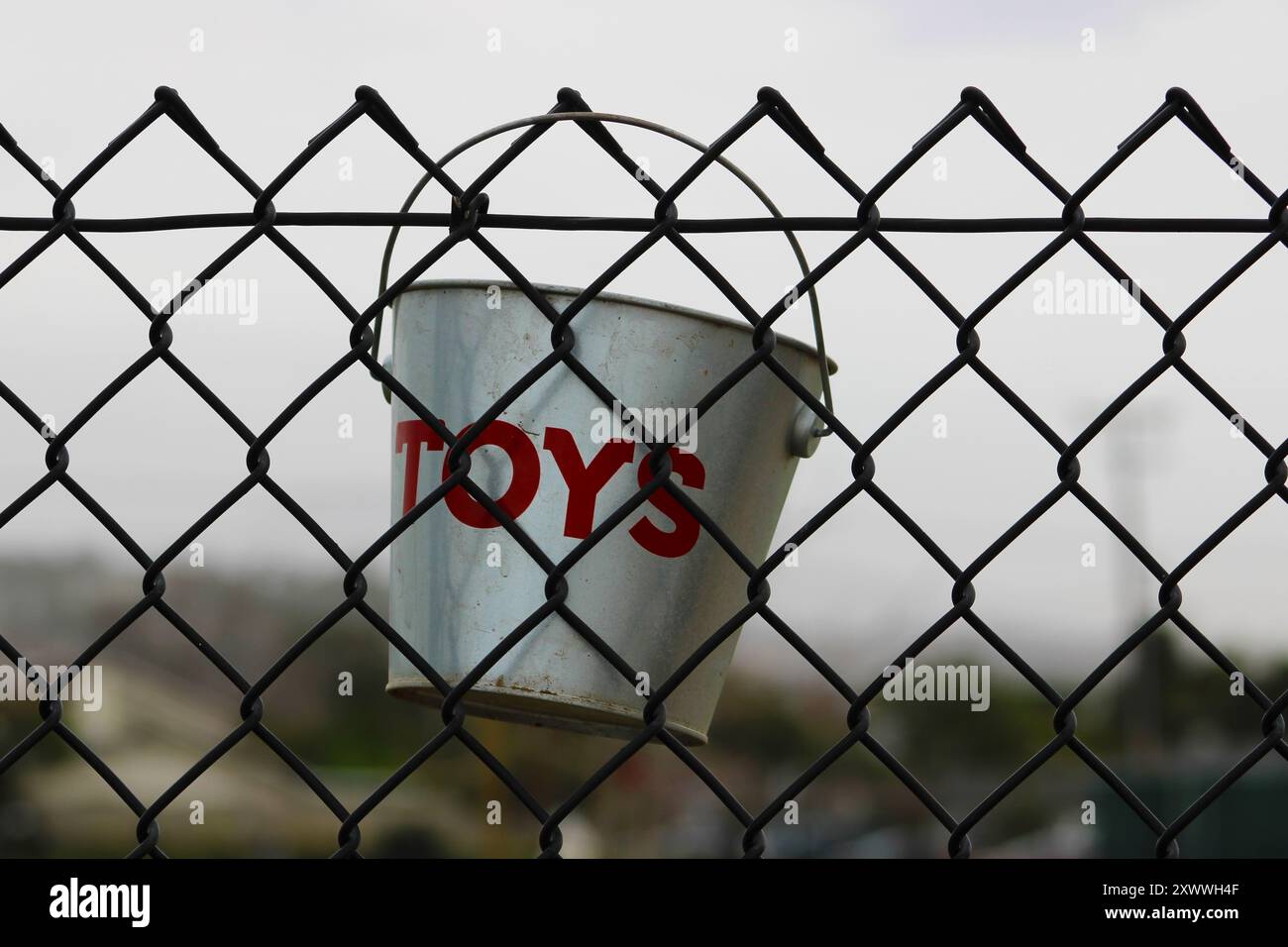 silver tin toy bucket hanging on black chain link fence Stock Photo - Alamy