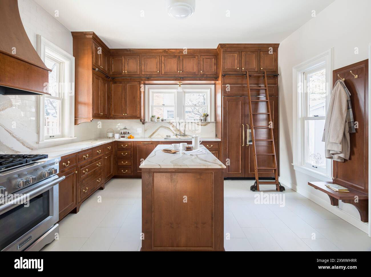 An updated version of a traditional kitchen with dark stained cabinets and a ladder and rail ...