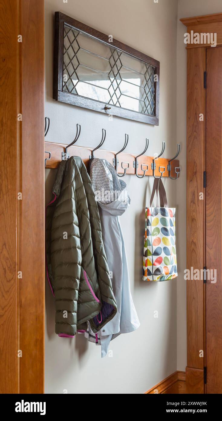 Jackets hanging on hooks in back entry mudroom Stock Photo - Alamy
