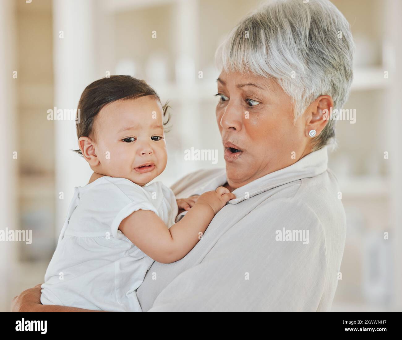 Crying, baby and grandmother with shock in home for worry, reaction and ...