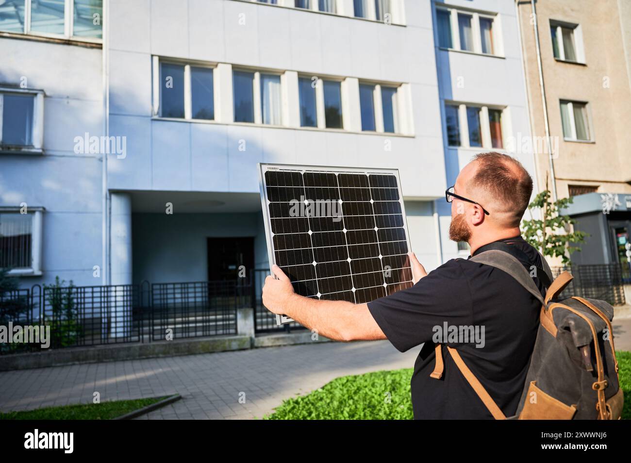 Man holding photovoltaic solar panel in front of historical building ...
