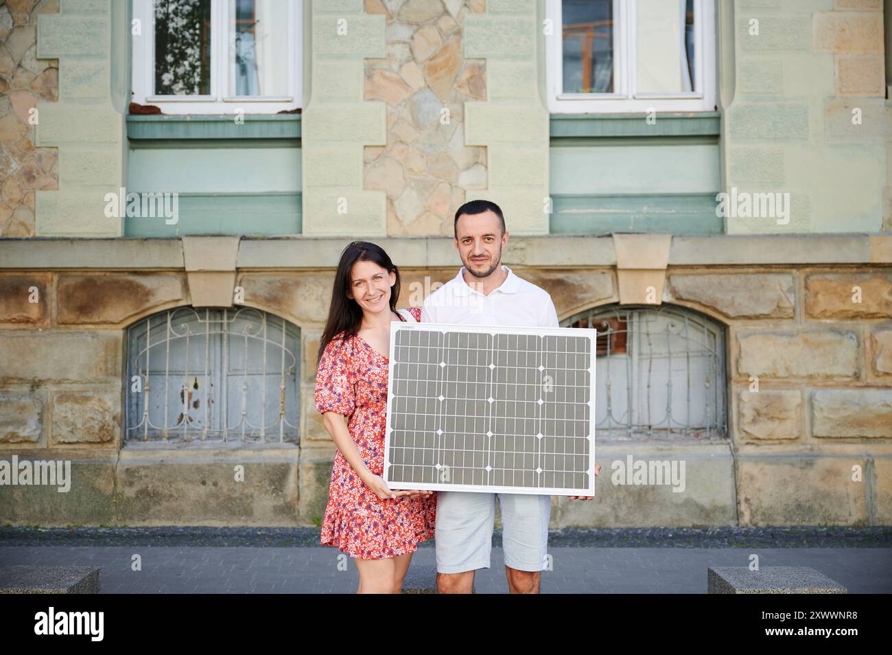 Cute couple holding portable solar panel. Young man and his wife ...