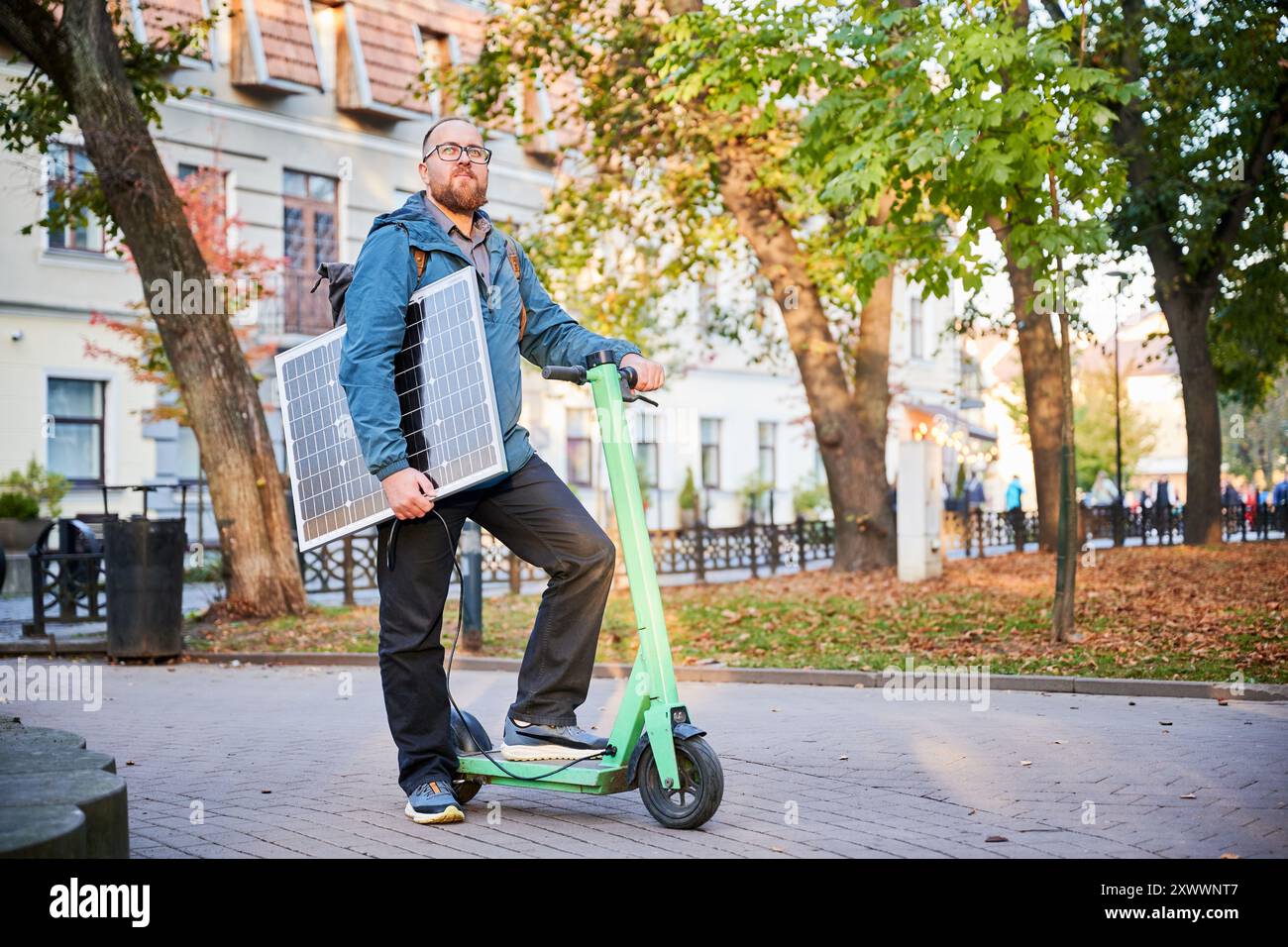 Man rides electric scooter while carrying solar panel. Integration of ...