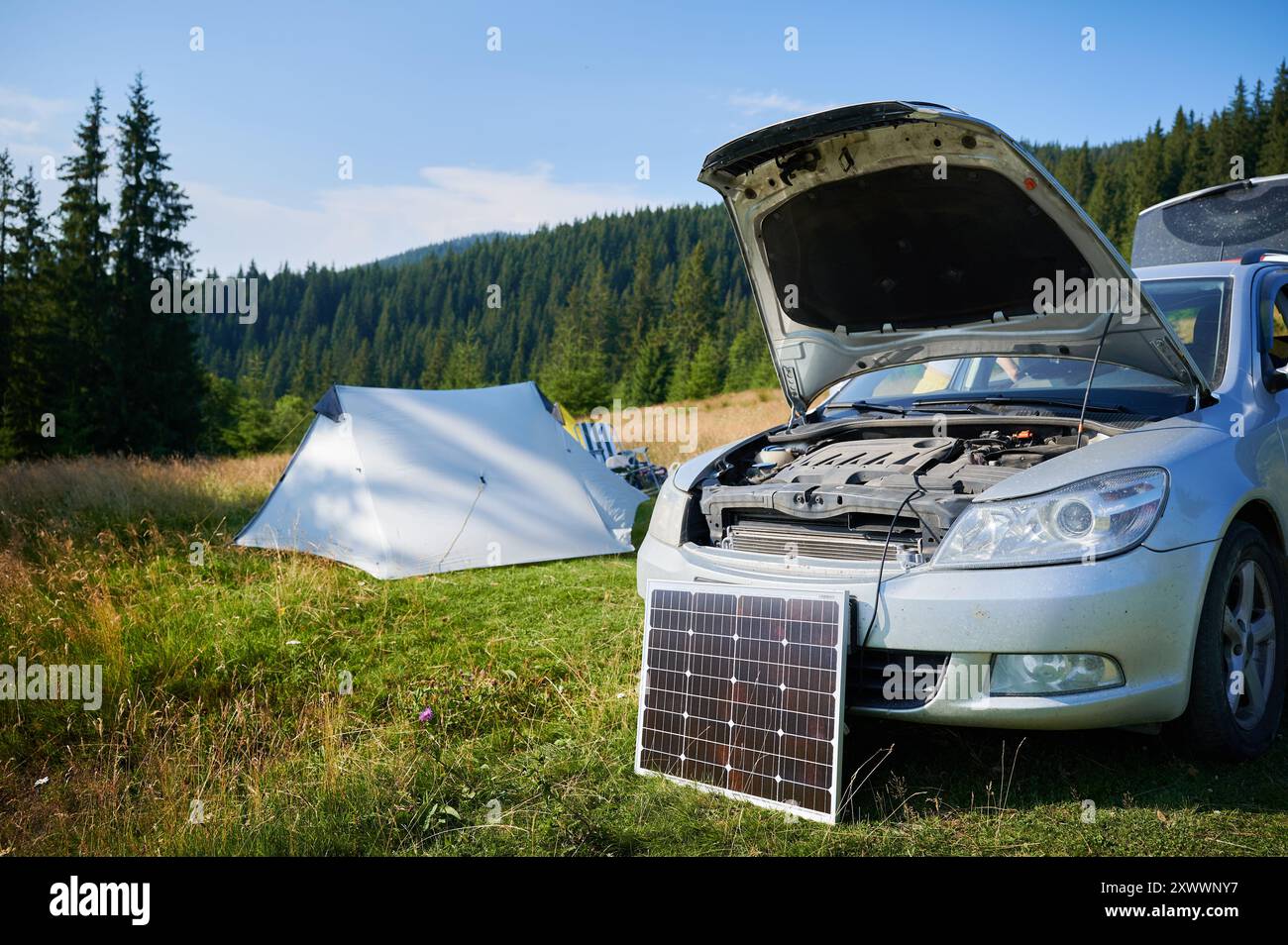 Solar panel in front of car with hood open, symbolizing transition from ...
