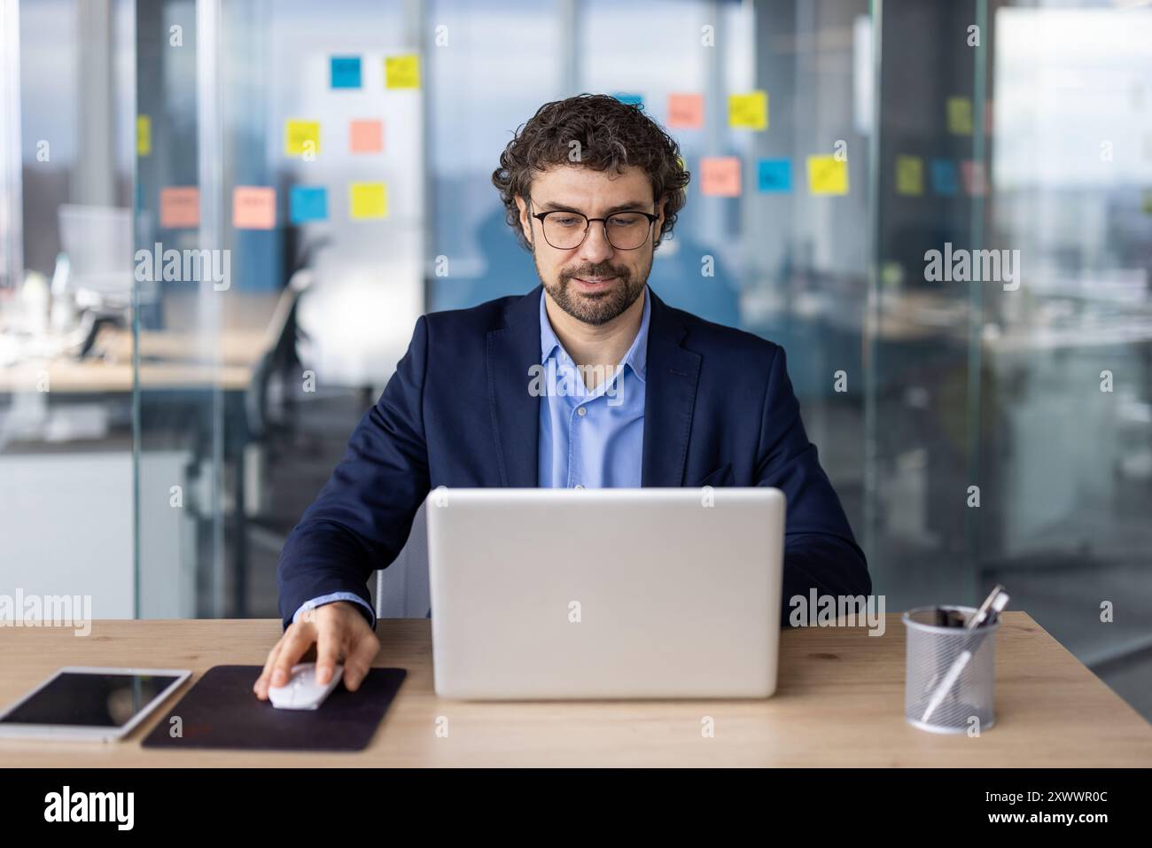 Business man in suit using a laptop in a modern office with glass walls ...