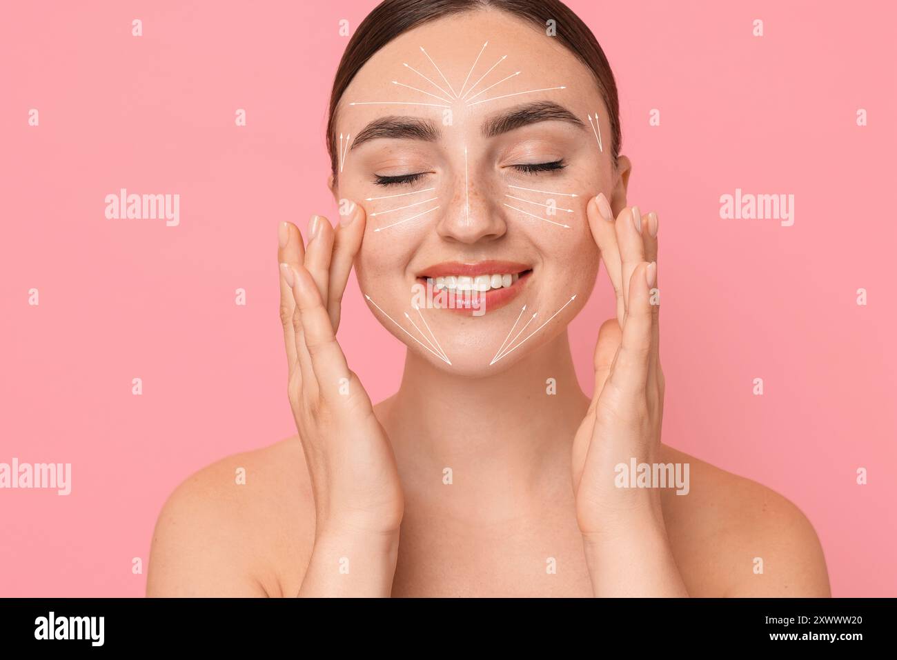 Beautiful young woman doing face massage with fingers on pink ...