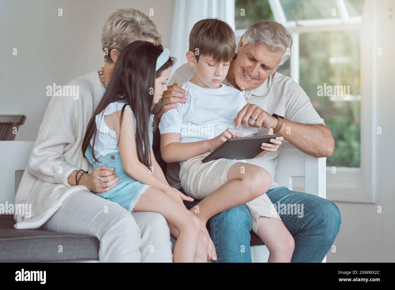 Tablet, children and grandparents in family home for relax, learning ...