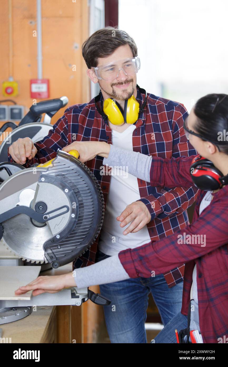 foreman training female worker to use circular saw Stock Photo - Alamy