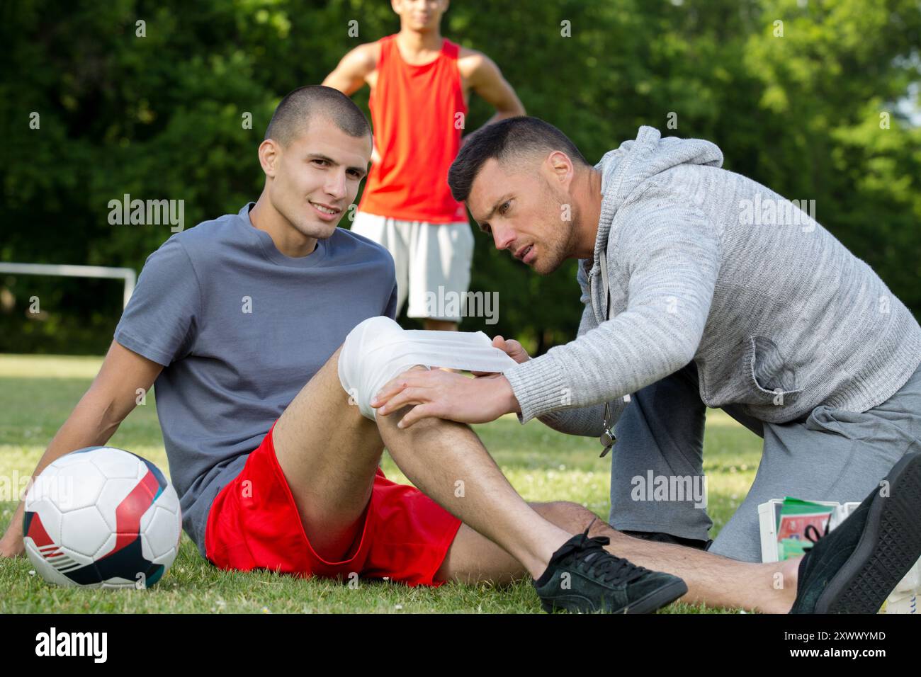 trainer bandaging athletes knee injury Stock Photo - Alamy