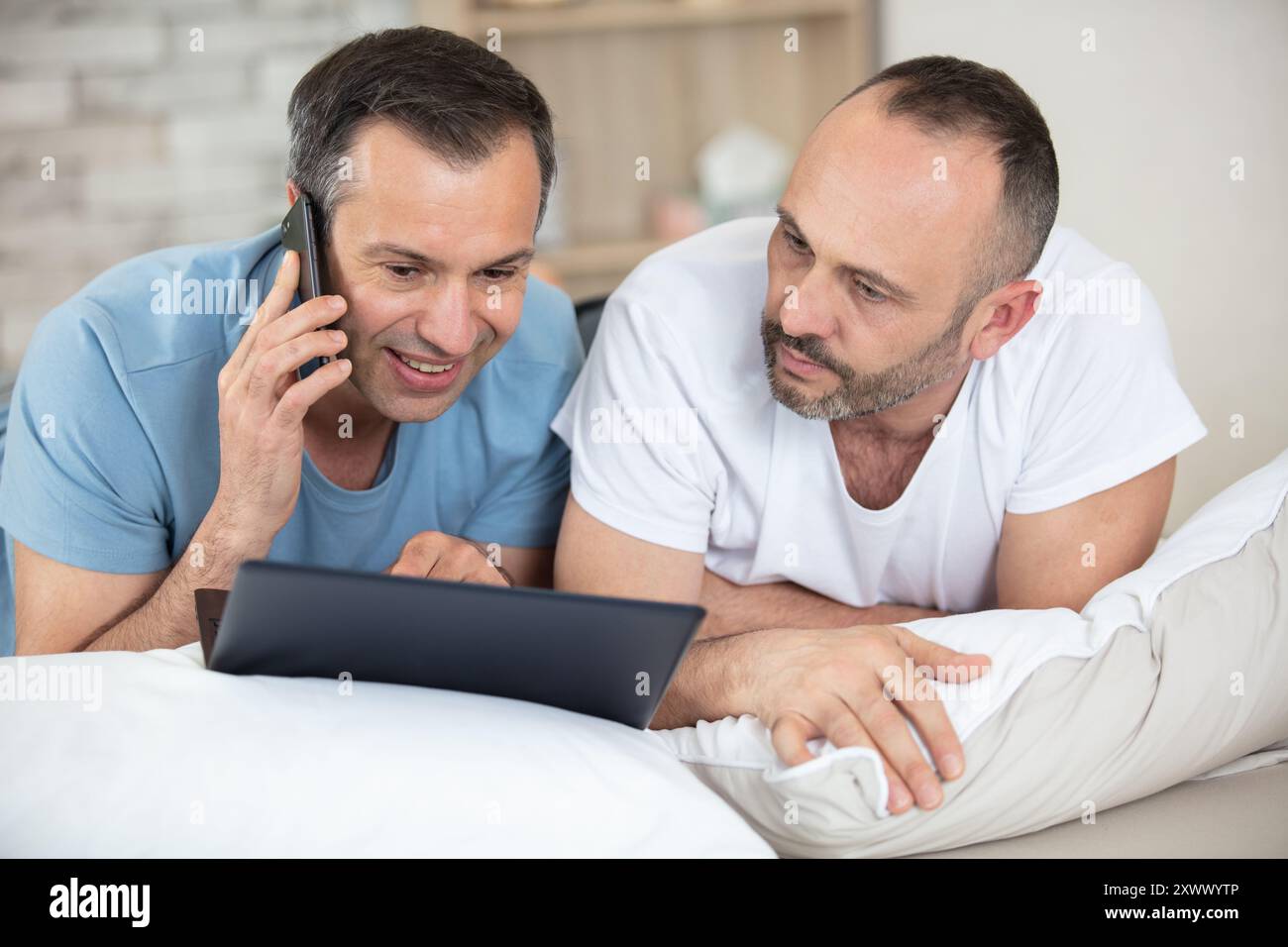 two people on the phone checking a tablet Stock Photo - Alamy