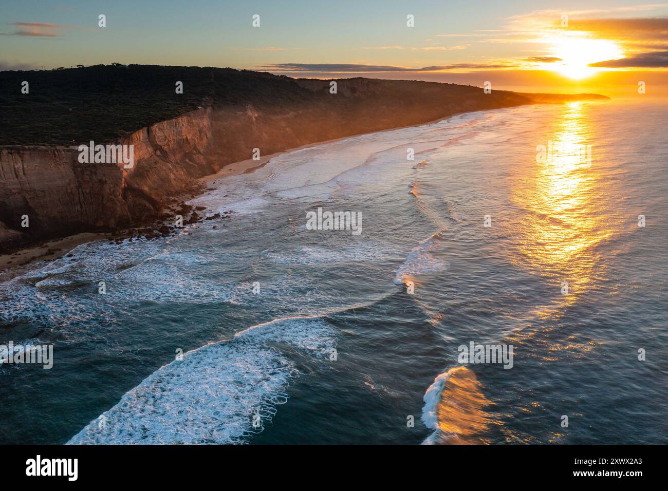 Aerial view of waves crashinf on the base of sea cliffs during sunrise ...