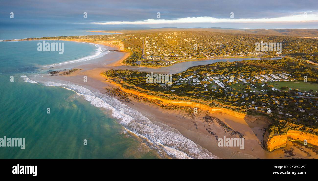 Aerial panorama of a river flowing out to sea through a costal town at ...
