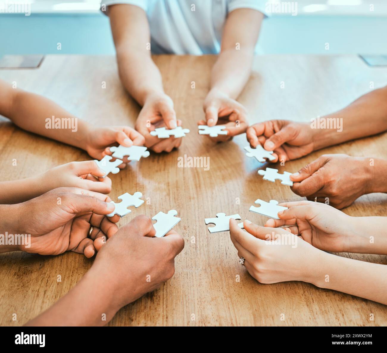 Collaboration, hands and puzzle with business people at wooden table ...
