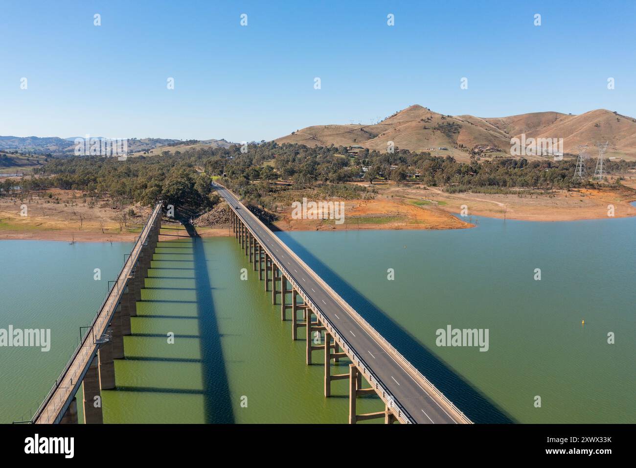 Aerial view of twin bridges over a reservoir surrounded by hills at ...