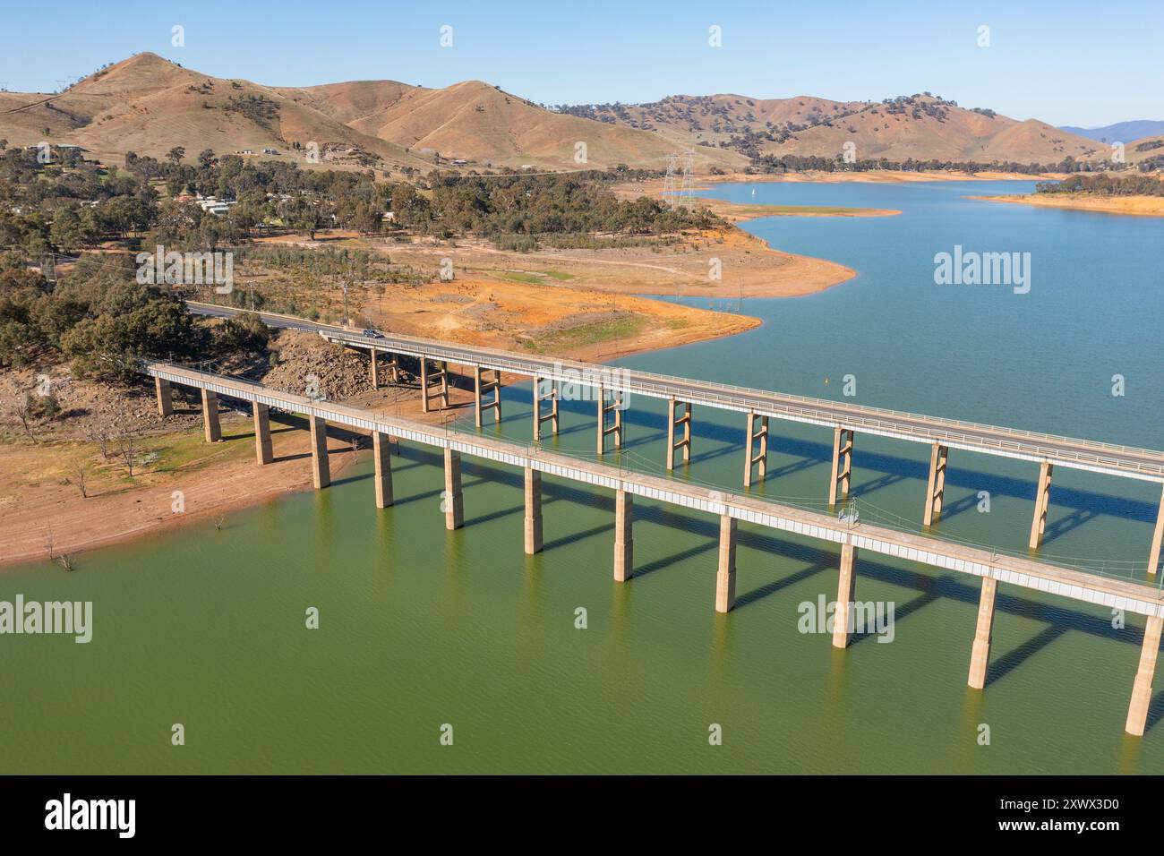 Aerial view of twin bridges over a reservoir surrounded by hills at ...