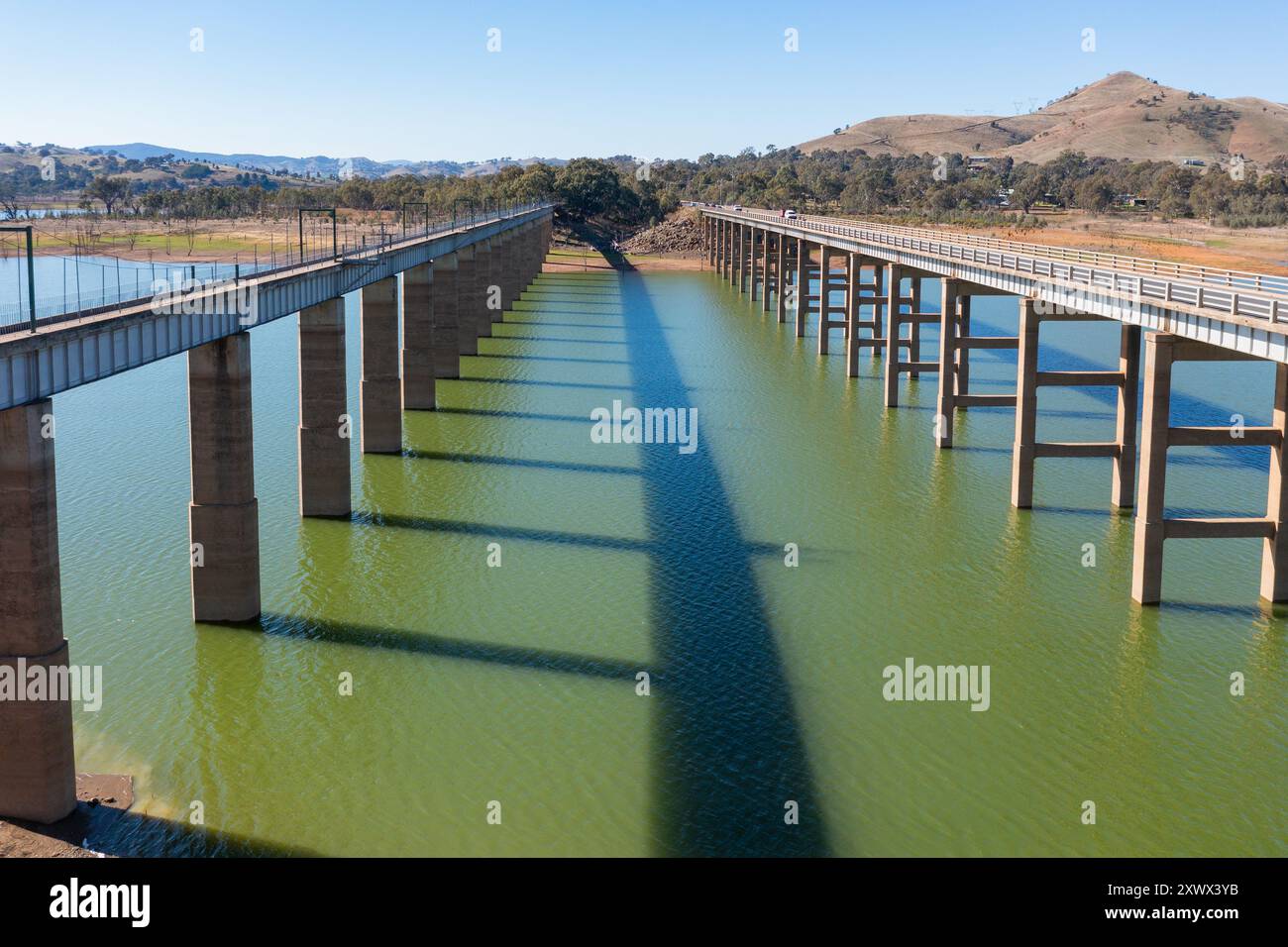 Aerial view of twin bridges over a reservoir surrounded by hills at ...