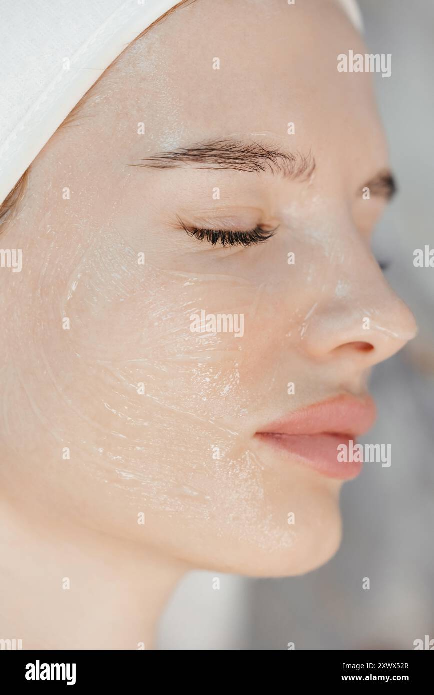 The cosmetologist applies transparent gel on the face of young female ...