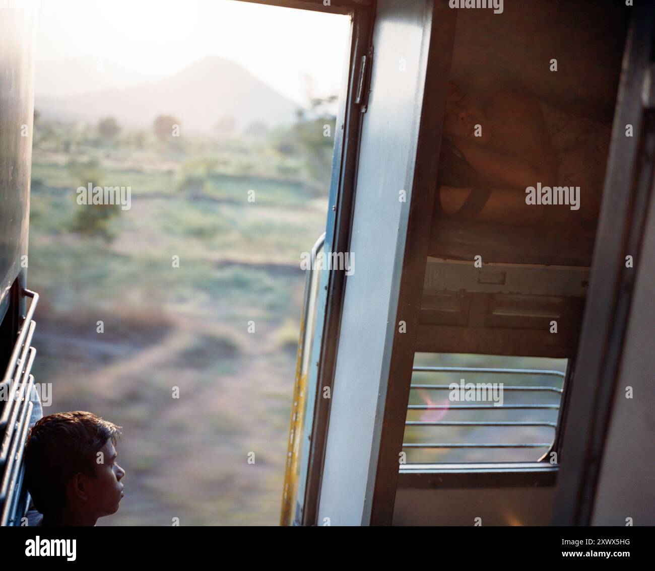A contemplative boy looking out of a train window while traveling from ...
