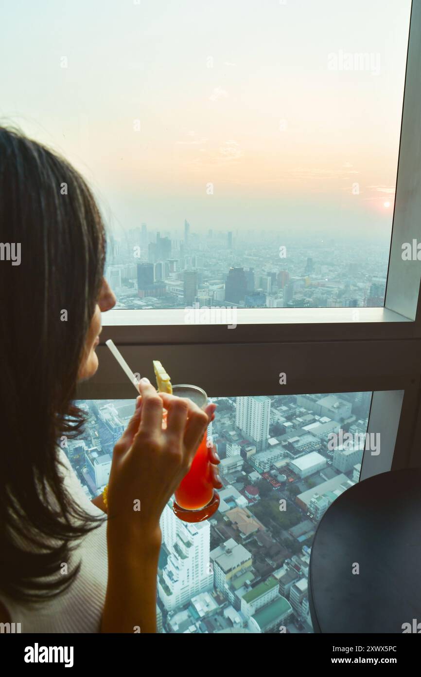 Close up young beautiful woman sit hold red color cocktail drink on sky ...