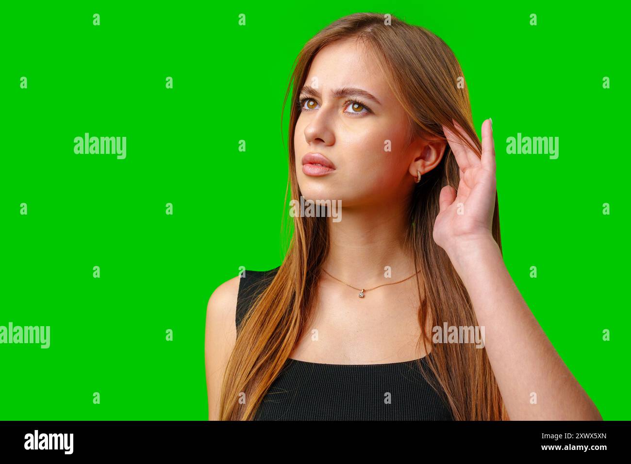 Young Woman Listening Intently Against a Green Screen Stock Photo - Alamy