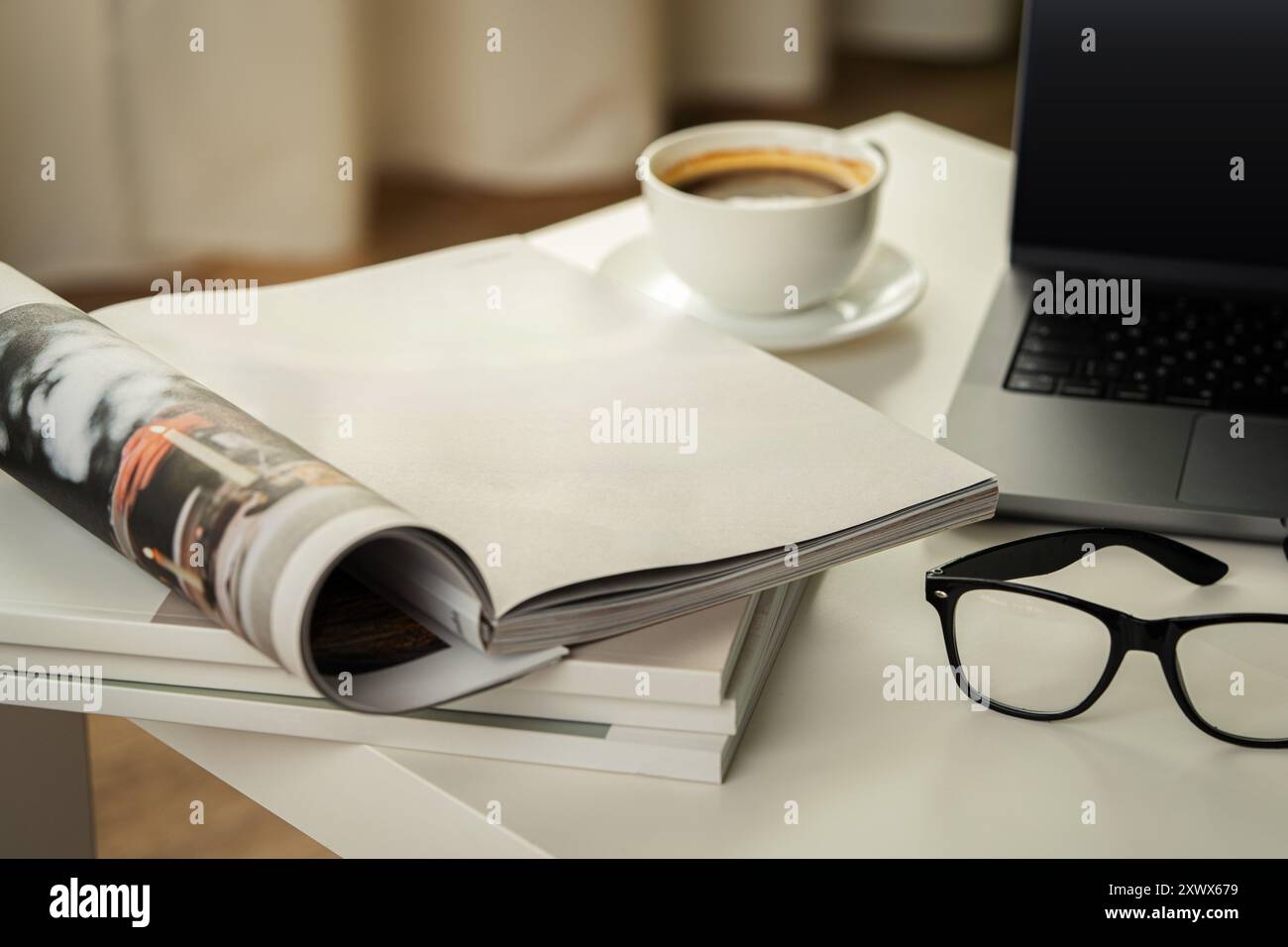 Modern Workspace With Laptop, Glasses, and Magazines Stock Photo - Alamy