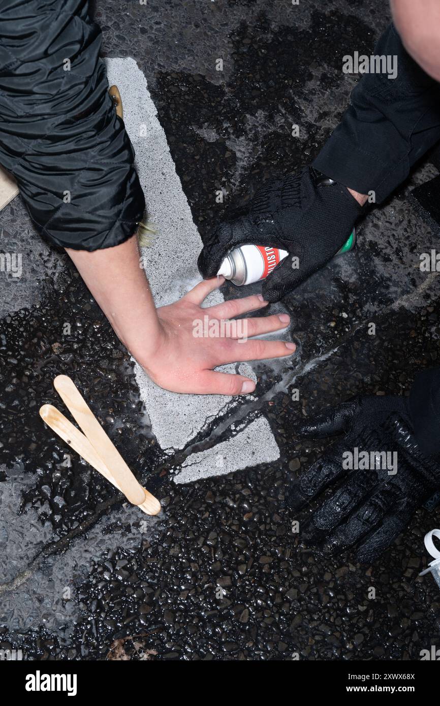 A photo capturing a climate activist's hand glued to the street being ...