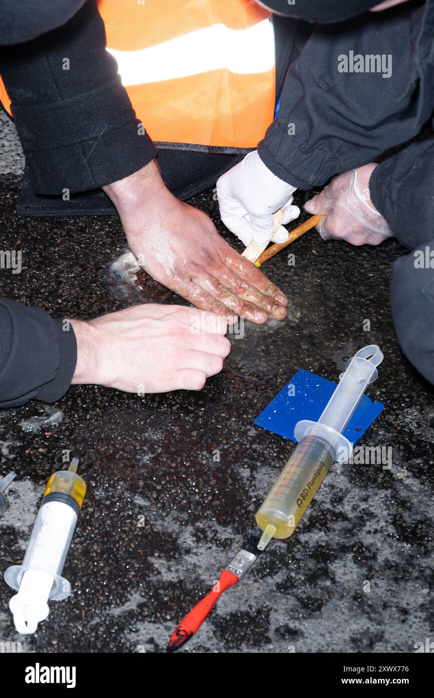 Climate activists from Letzte Generation glued to the street being ...