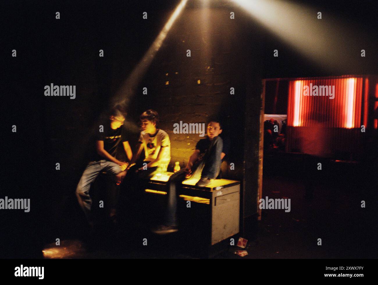 Three young men are sitting under a dramatic spotlight in Club MARIA am ...