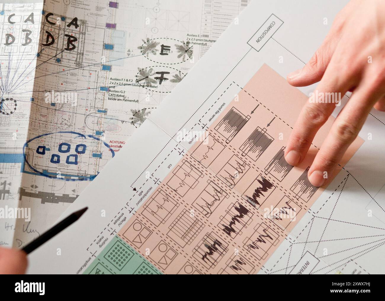 A close-up of hands working with engineering diagrams and graphs. The ...