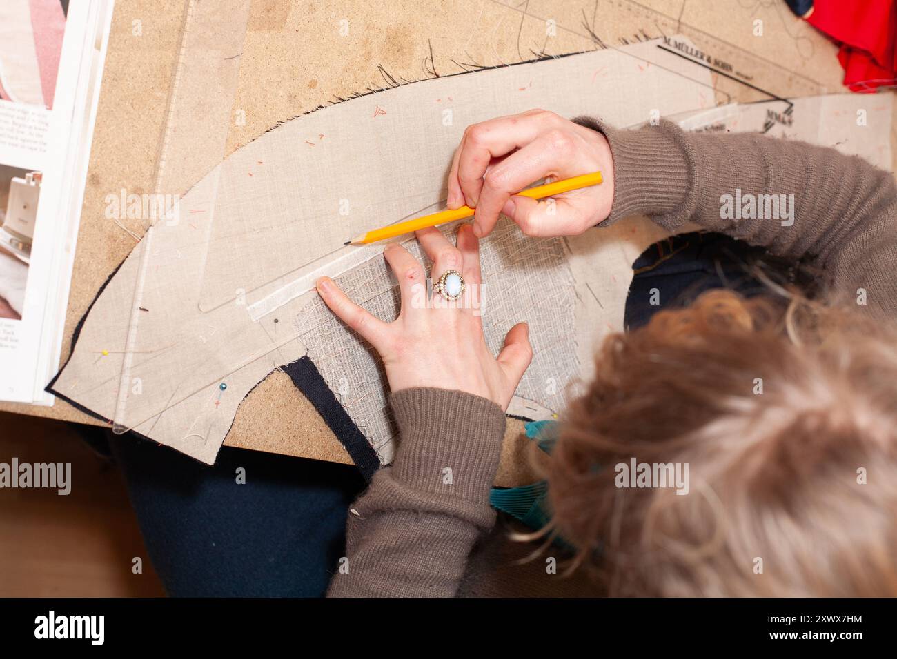 Top view of a person using a pencil to draw lines on sewing patterns ...